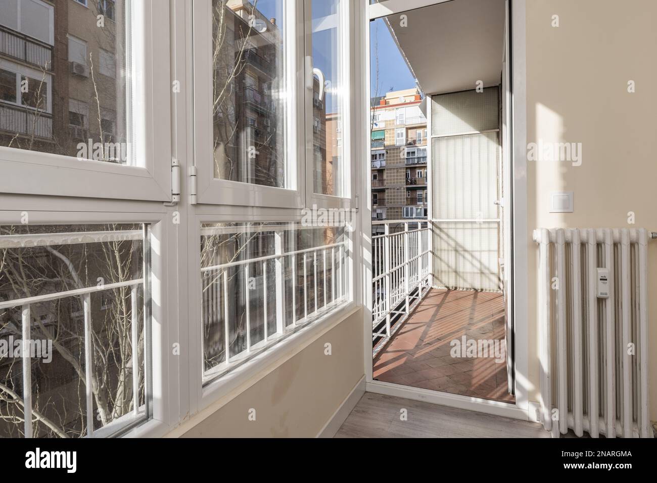 Glazed part of a terrace next to a white aluminum exit door to the open ...