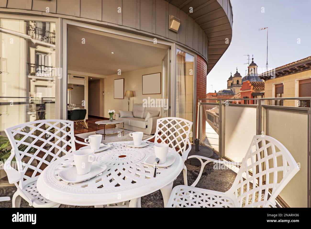 Urban terrace with a white circular outdoor table with a set of ...