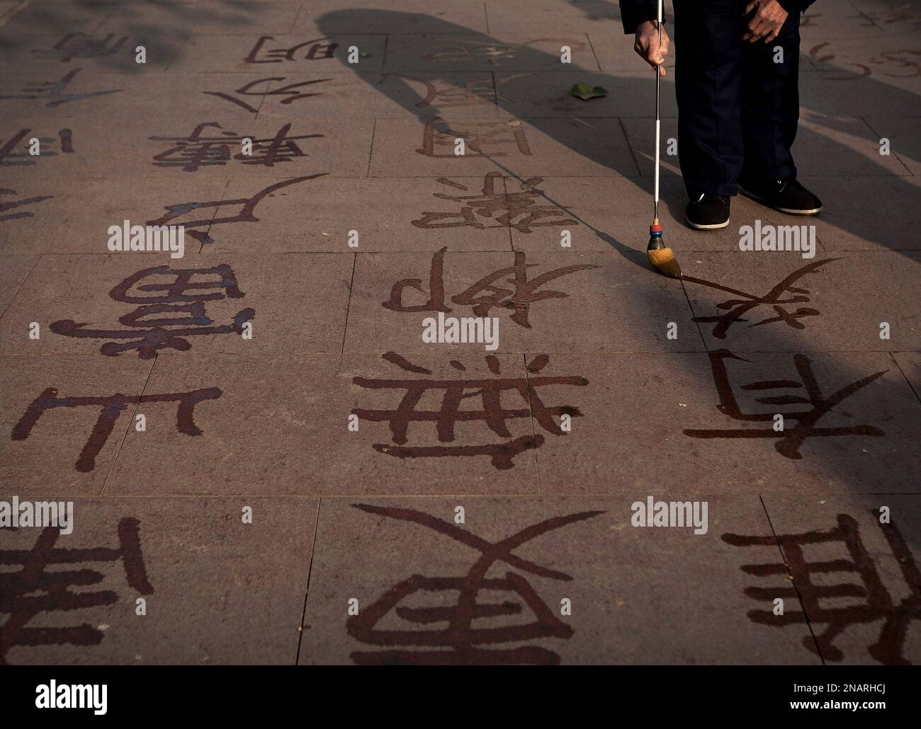 An elderly man uses water to practice writing of Chinese characters on ...