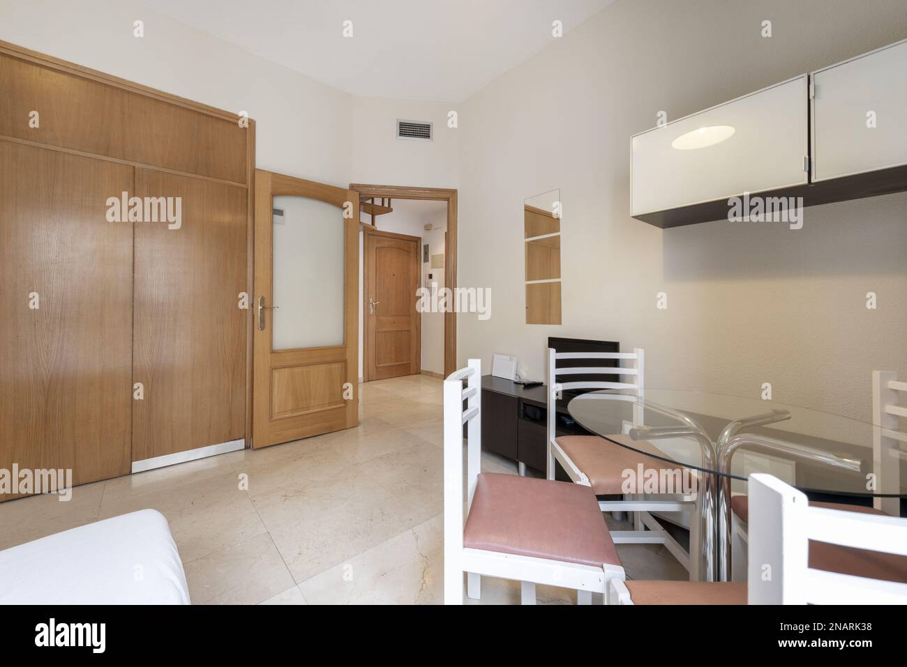 Studio apartment with kitchenette with closed wooden doors, round glass ...