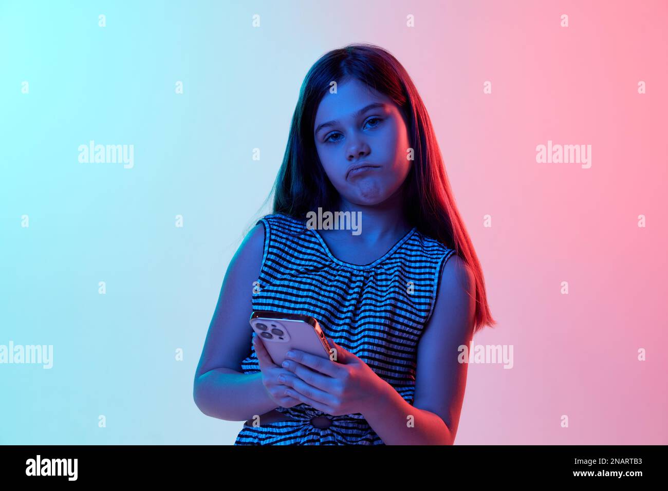 Doubtful face. Little emotive girl, child posing with mobile phone over ...