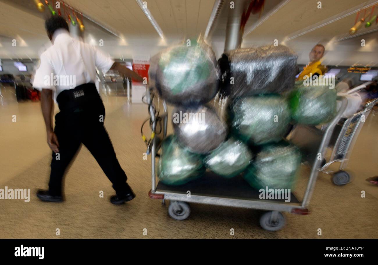 A skycap pulls a cart full of luggage as people travel during the busy ...