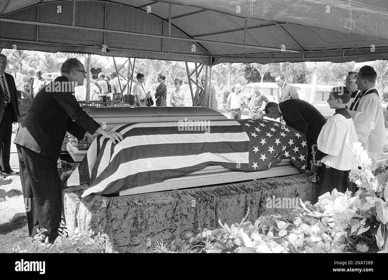 An altar boy and priests stand at the right as a funeral director ...