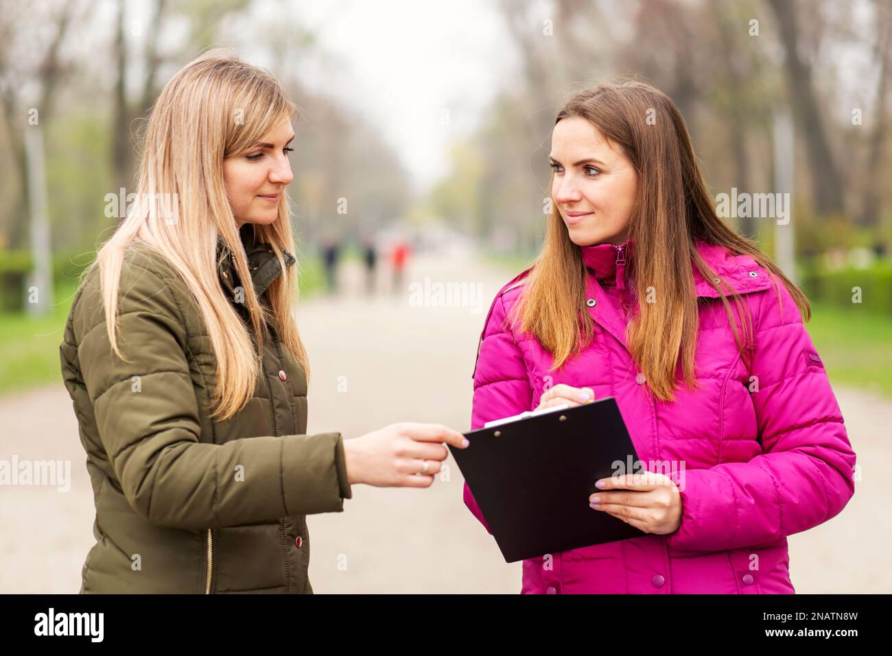 Opinion poll. A woman interviewing people, conducting survey standing ...