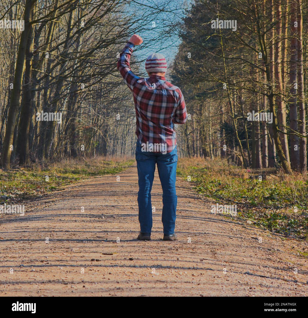 Man stood on a path in the woods forward facing and waving ahead with ...