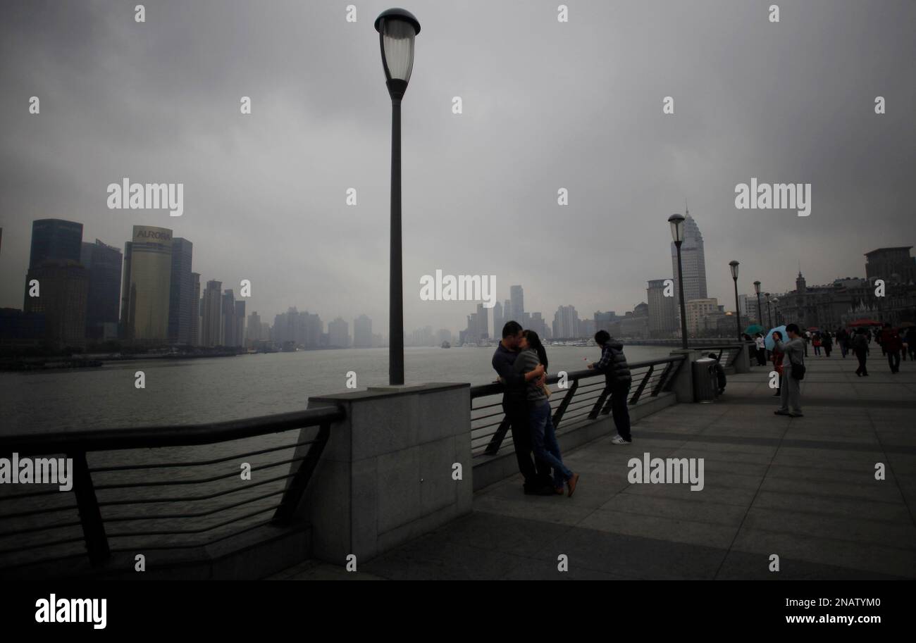 A man and a woman kiss at the river front promenade called "the Bund ...