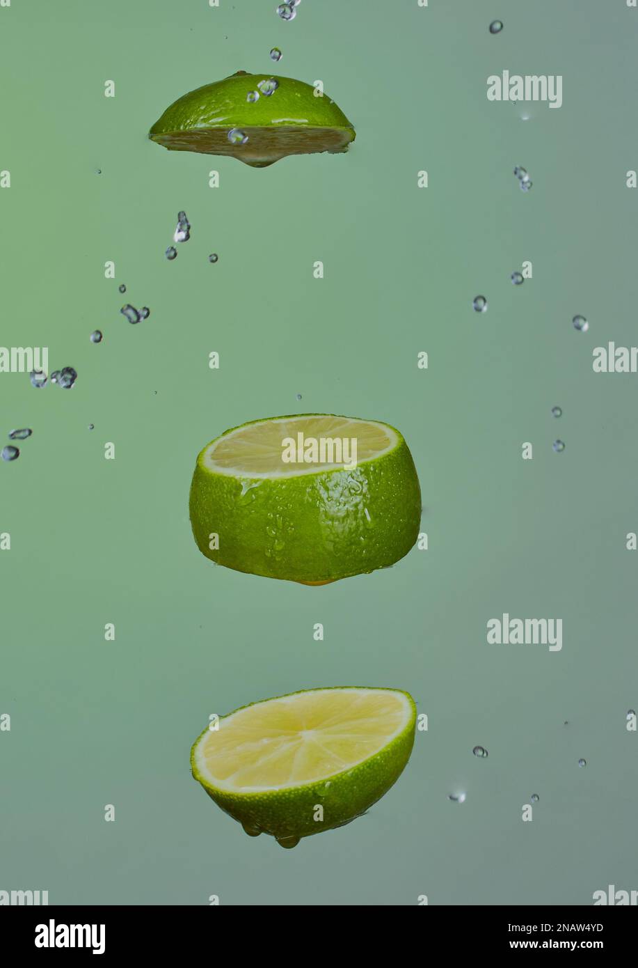 Sliced lime segments floating in the air, with water droplets hitting ...