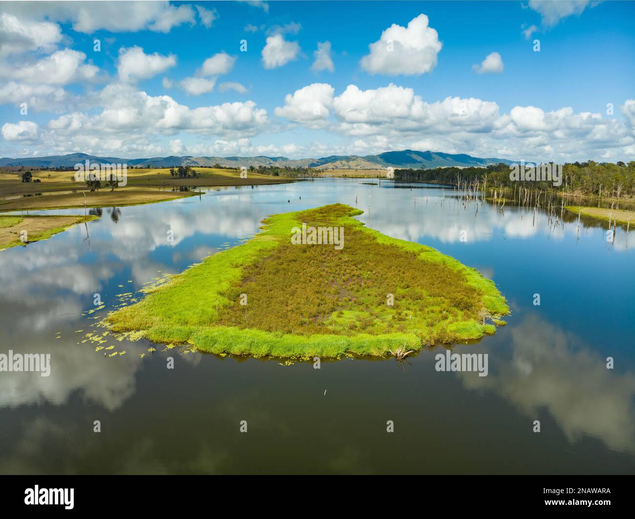This image depicts a long lagoon surrounded by grass on top of a dry ...
