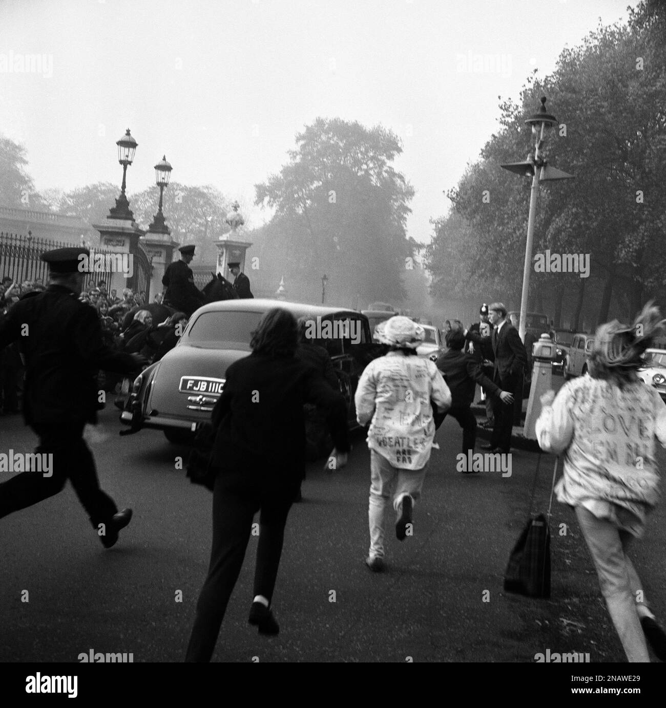 Police run after the fans chasing the limousine carrying the Beatles ...