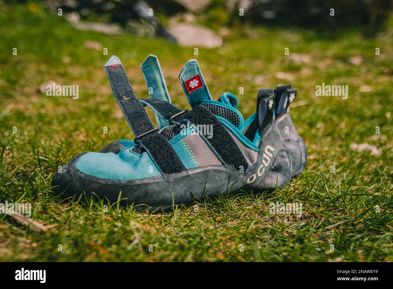 A close up of dirty-blue Ocun Strike LU Climbing shoes on a grass field ...