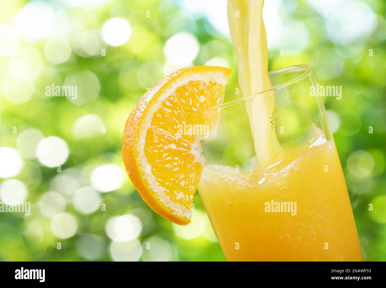 orange juice pouring into glass on green background Stock Photo - Alamy