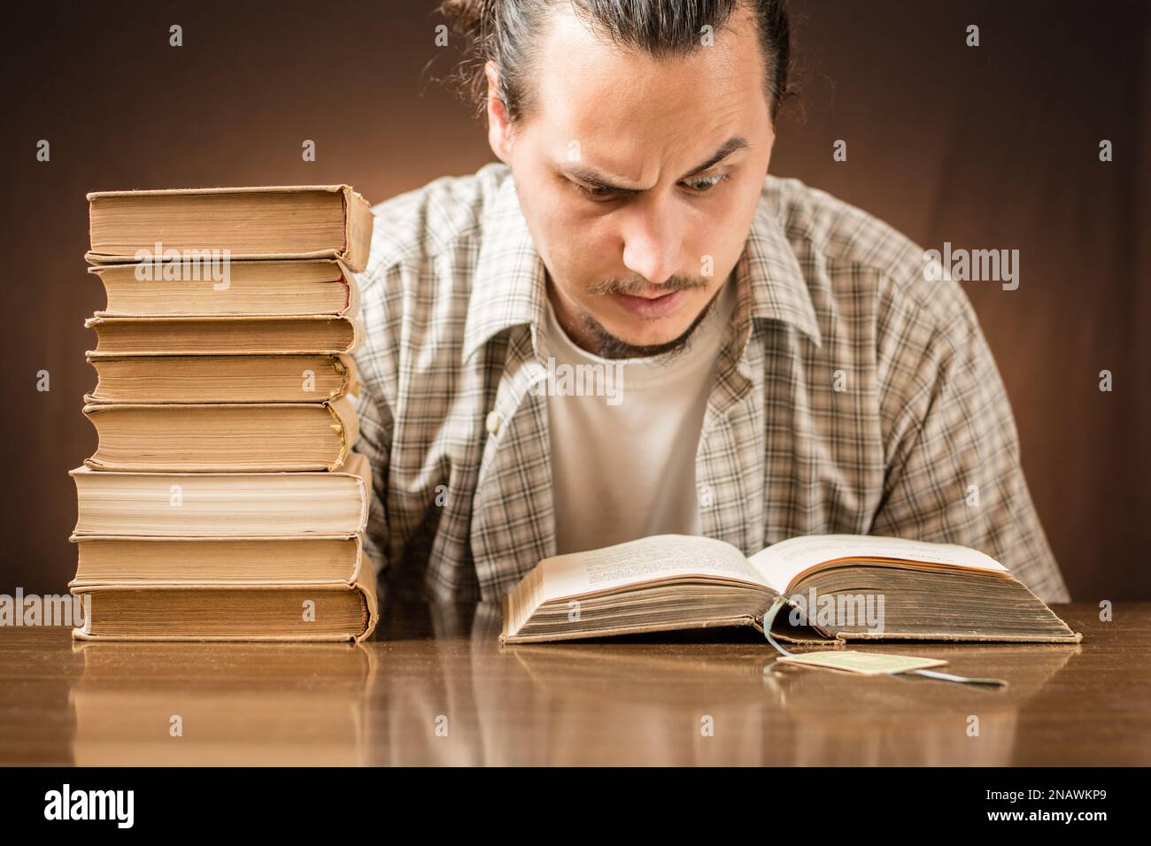 The angry student sitting on the desk with books Stock Photo - Alamy