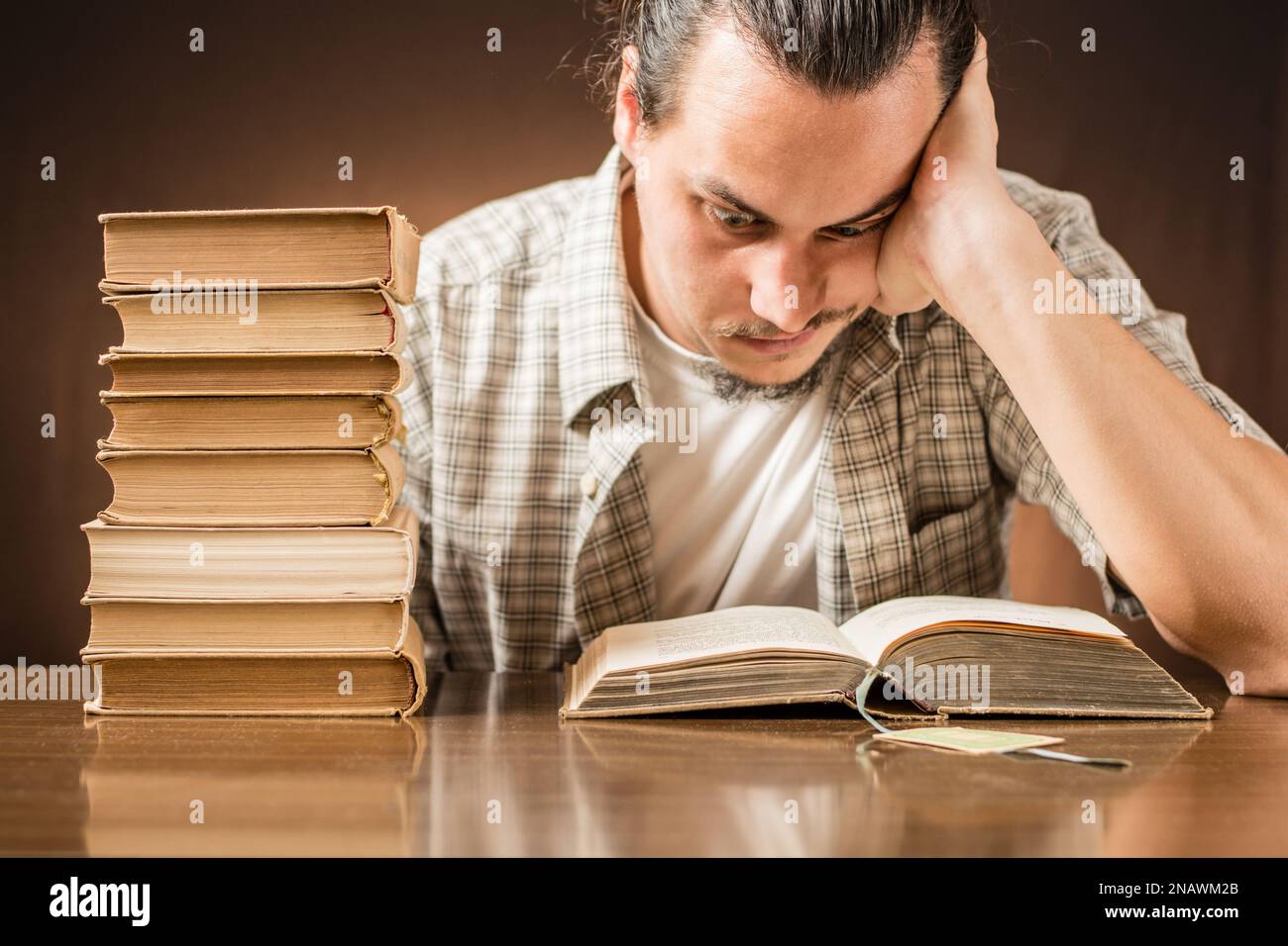 The angry student sitting on the desk with books Stock Photo - Alamy