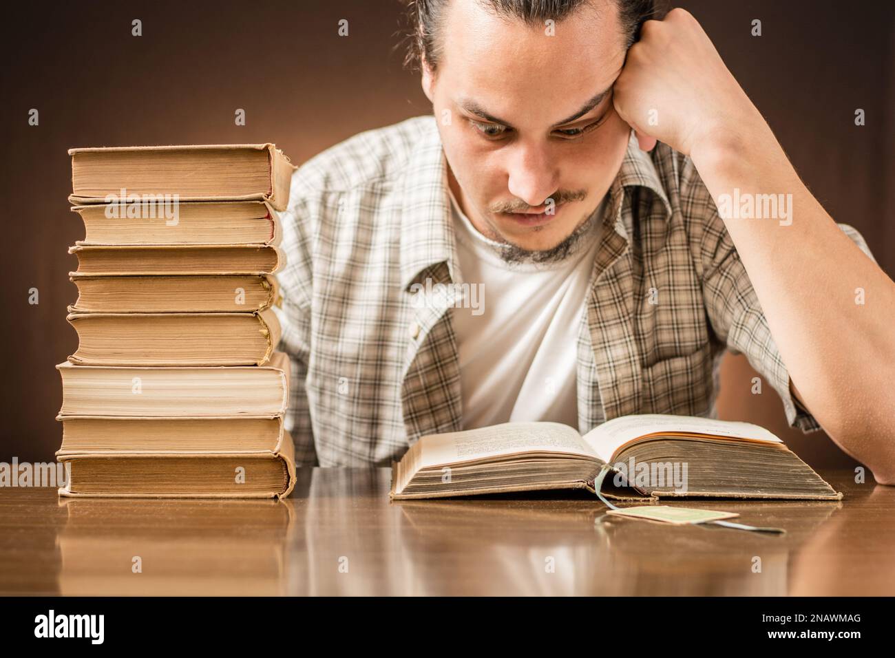 The angry student sitting on the desk with books Stock Photo - Alamy
