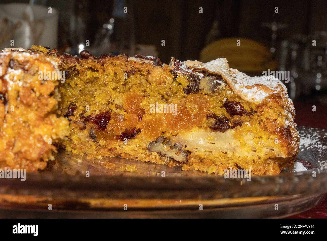 Sideview on a cut open cake with dried fruits, pecan nuts and apple ...