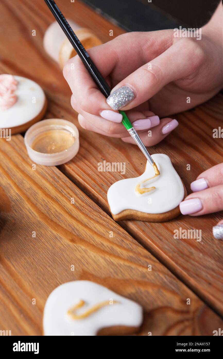 Female baker coloring gingerbread with powder Stock Photo - Alamy