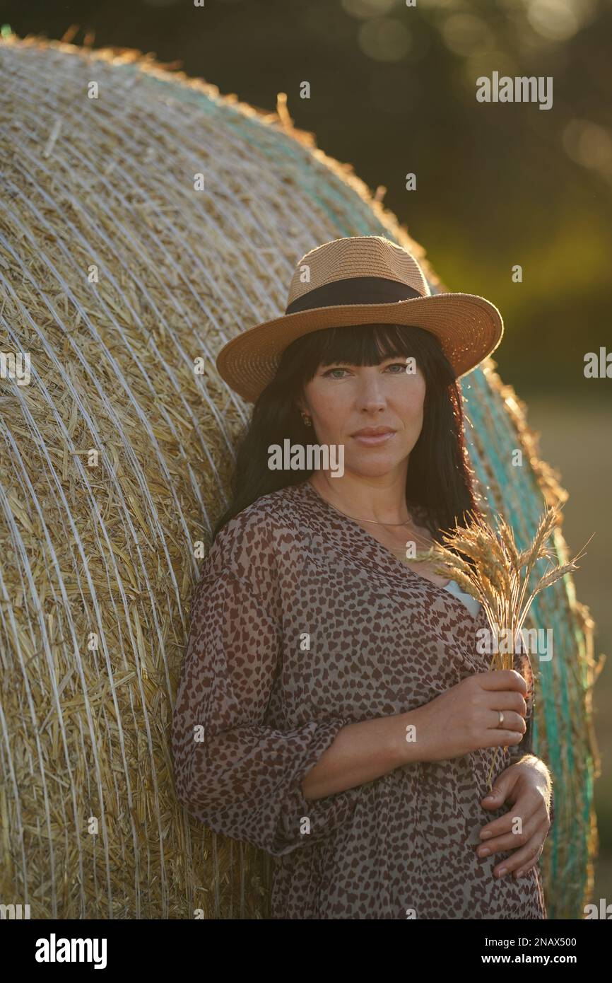 Pregnant beauty with black long hair leaned on a haystack, she was ...