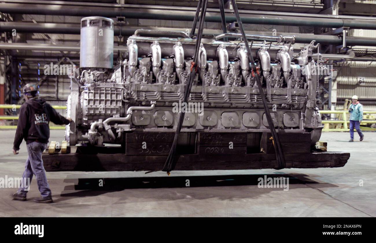 A worker directs one of two WWII submarine diesel engines after ...