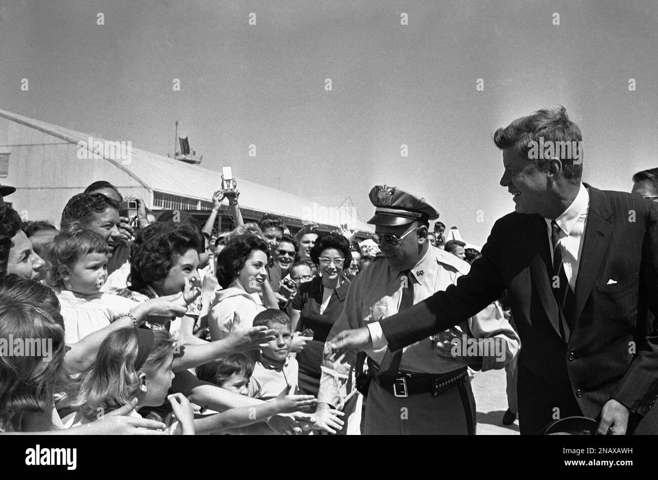 President John F. Kennedy reaches from his car to shake hands with ...