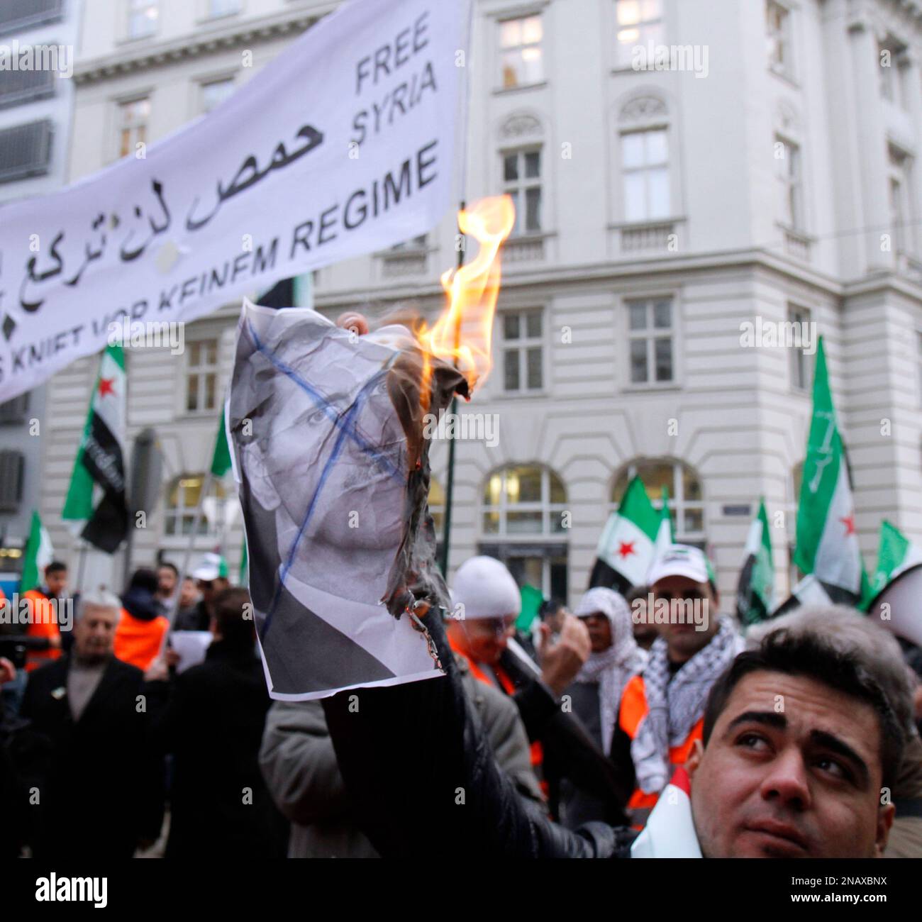 A protestor holds up a burning picture of Syria's President Bashar al ...