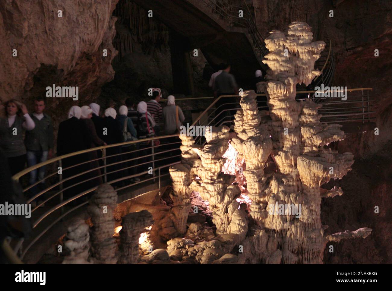 Tourists walk next to stalactites which are seen in the upper cave of ...