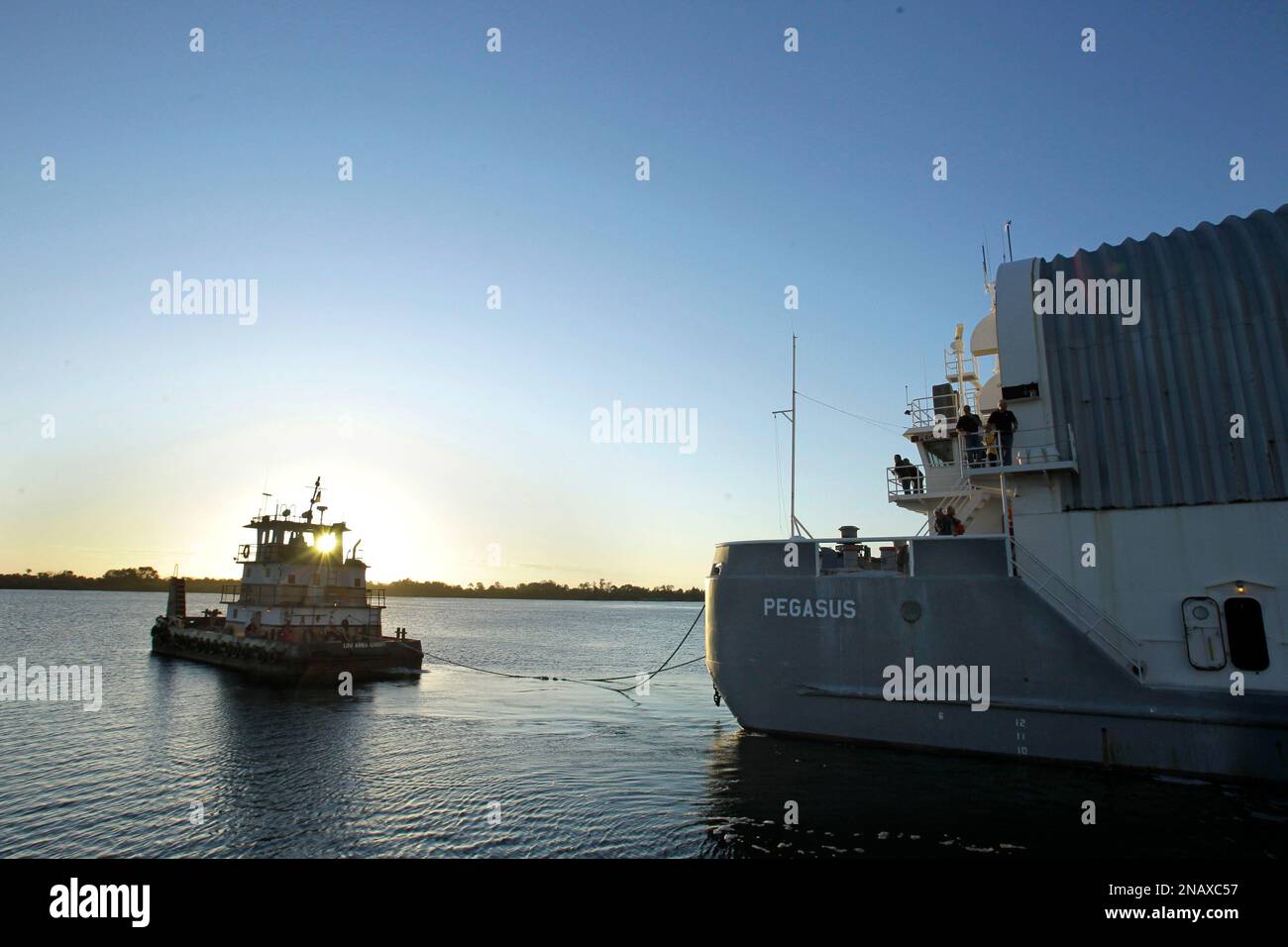 The Pegasus barge, center, guided by tugboats, leaves the Kennedy Space ...