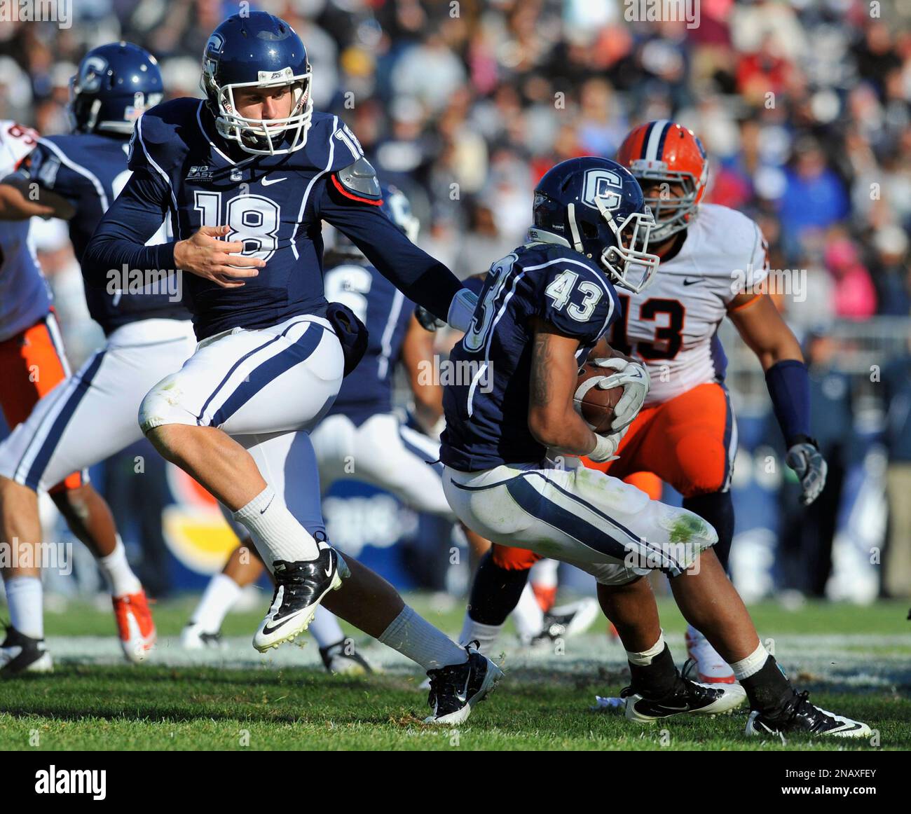Connecticut quarterback Johnny McEntee, left, hands off to Lyle McCombs ...