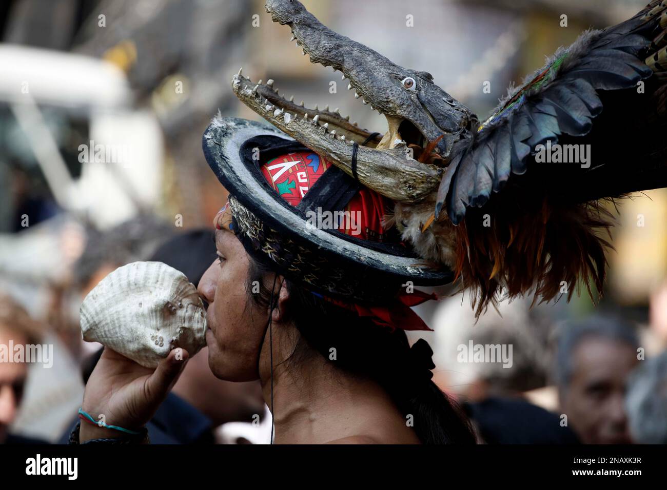 An Aztec dancer dressed in traditional costume plays a seashell ...
