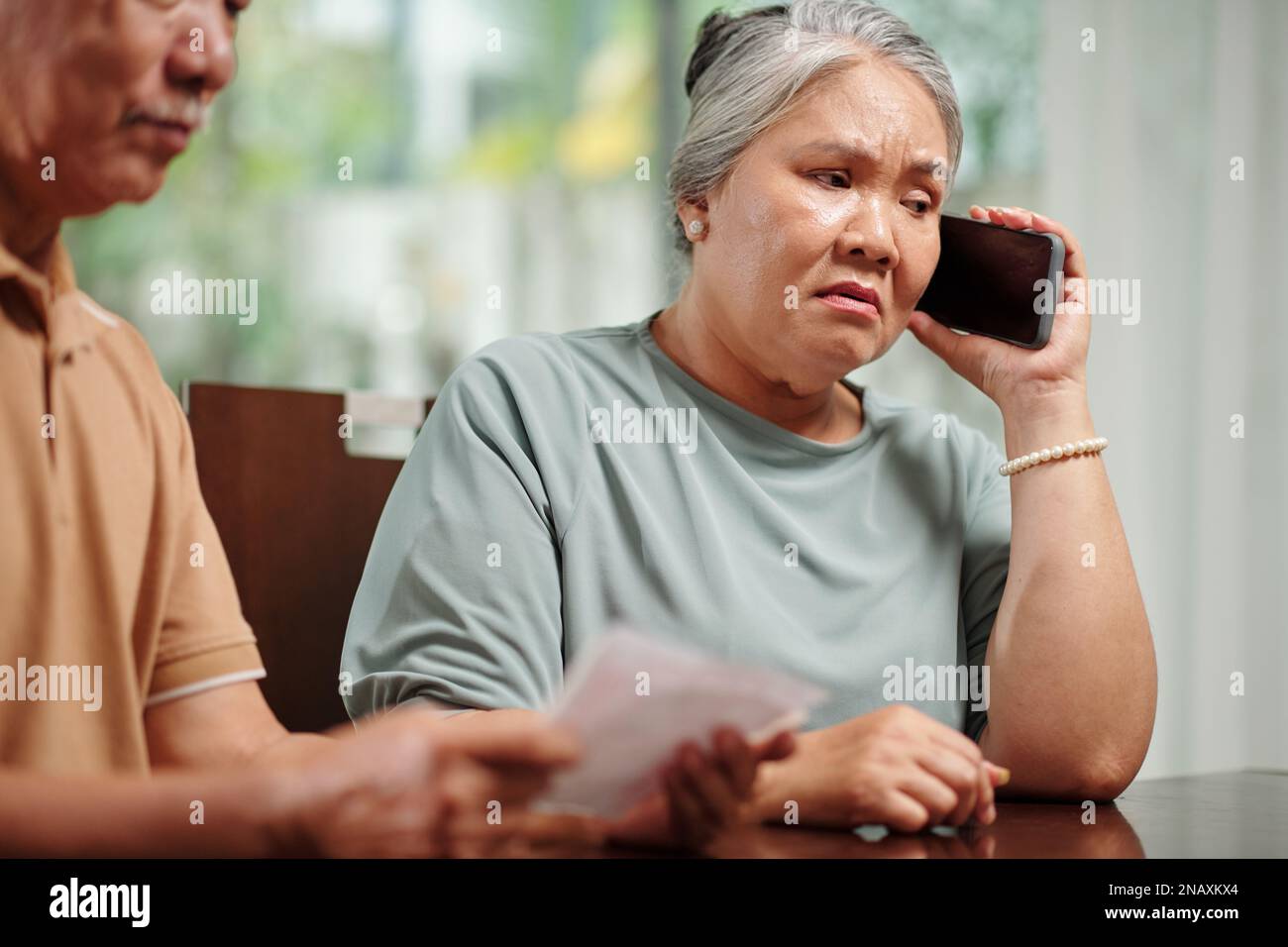 Sad senior woman receiving phone call from bank after missing credit ...