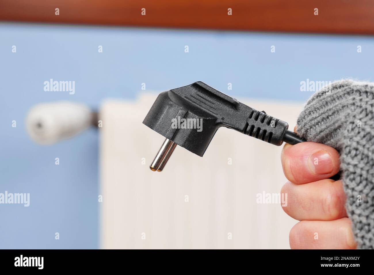 Disconnected electric plug of a convector heater in a frozen hand in a ...