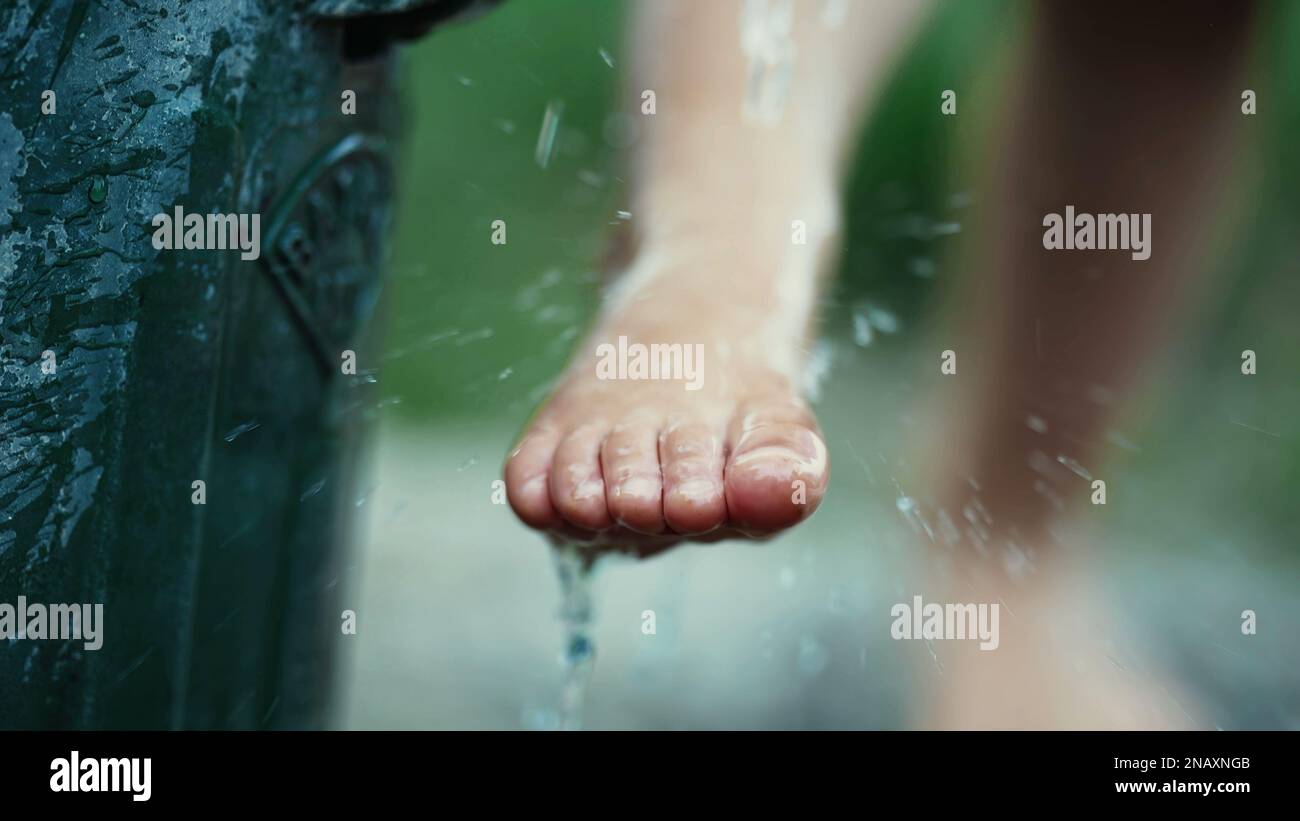 Child cleaning foot at water faucet outdoors. Kid cleaning body feet at ...