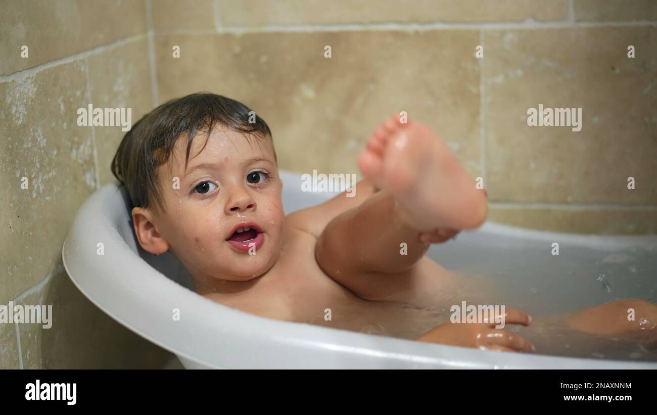 Cute baby bathing in small bathtub. Toddler boy washing routine bath ...