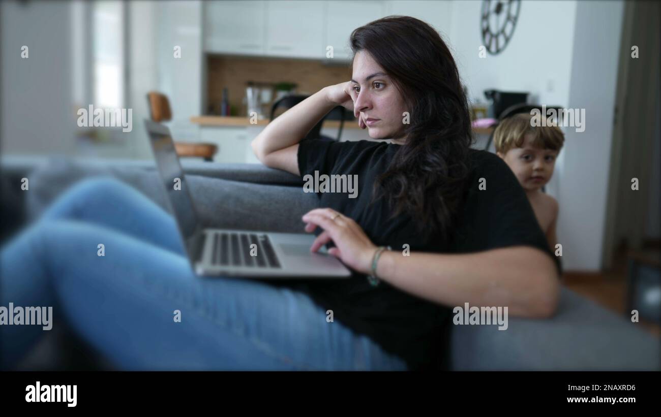 Woman browsing internet with laptop computer sitting on couch at home ...