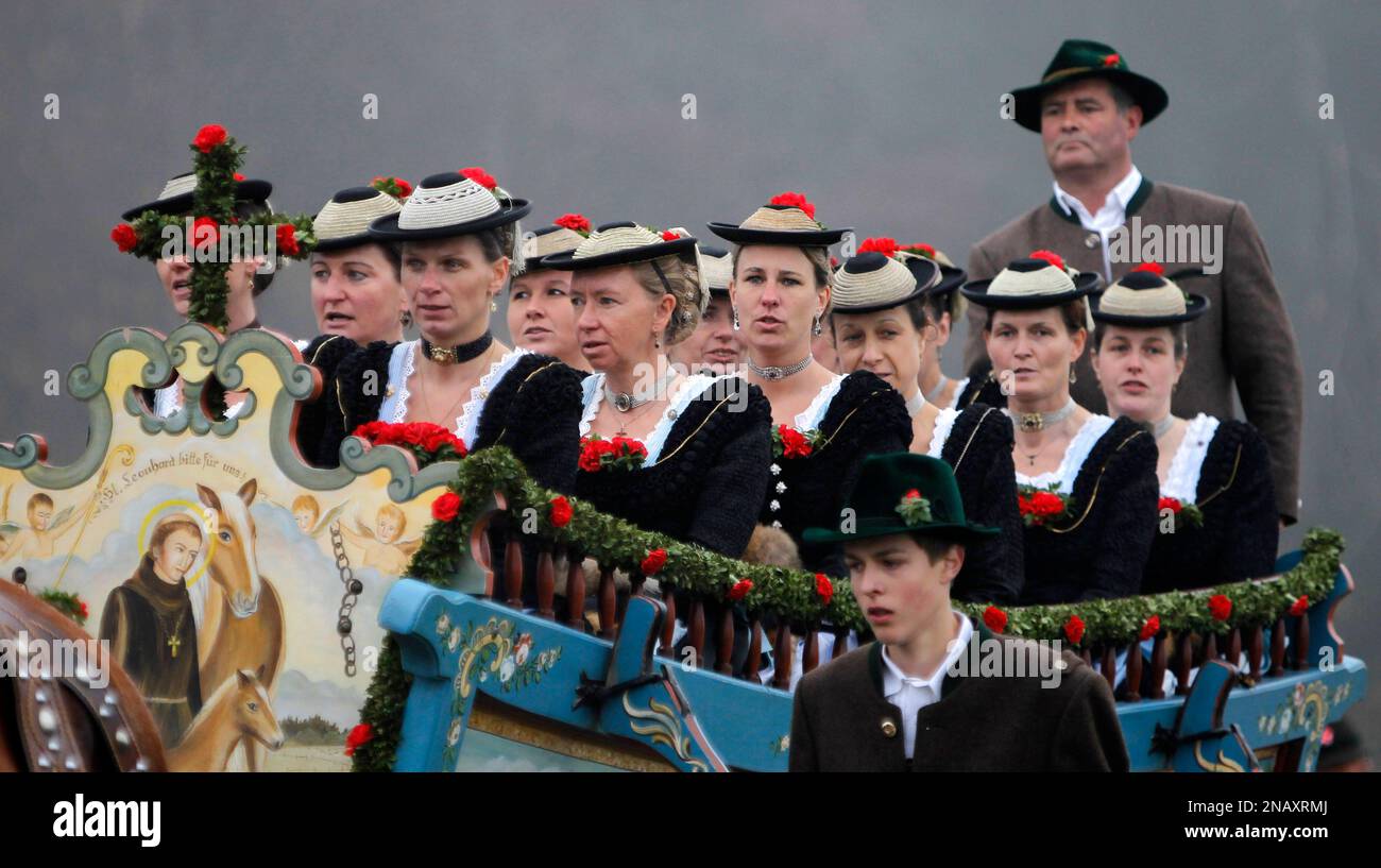 Women wearing the traditional costumes of the region sit in a horse ...
