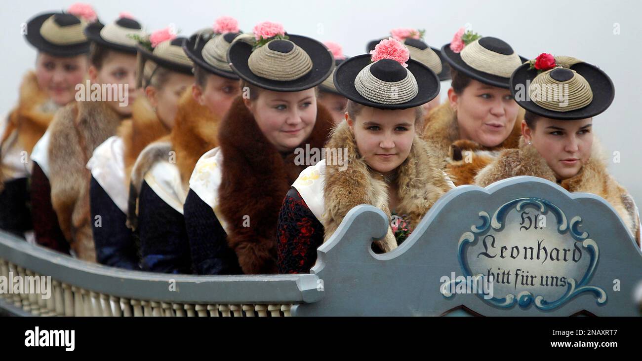 Women wearing the traditional costumes of the region sit in a horse ...