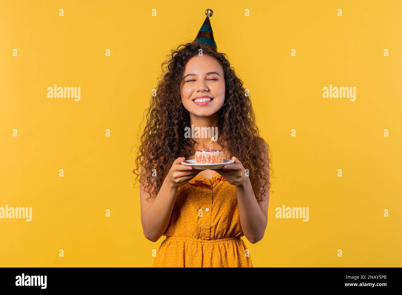 Birthday woman, curly hair making wish - candle on cake. Celebrating ...