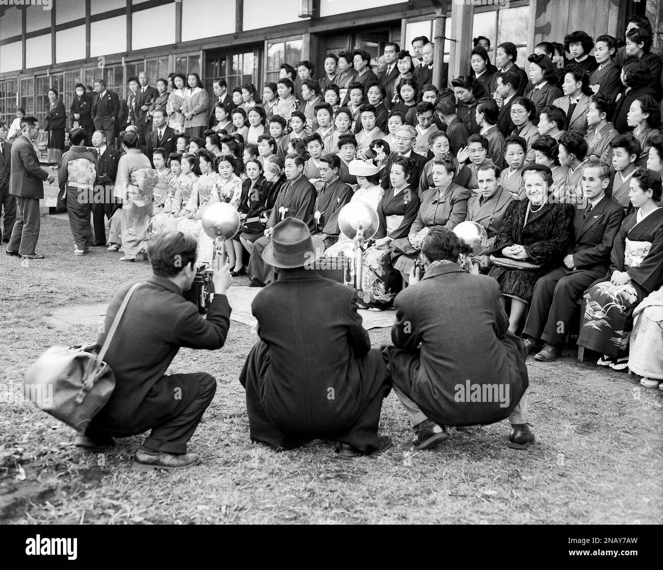 Realistically enacting the wedding, a couple poses with their family ...