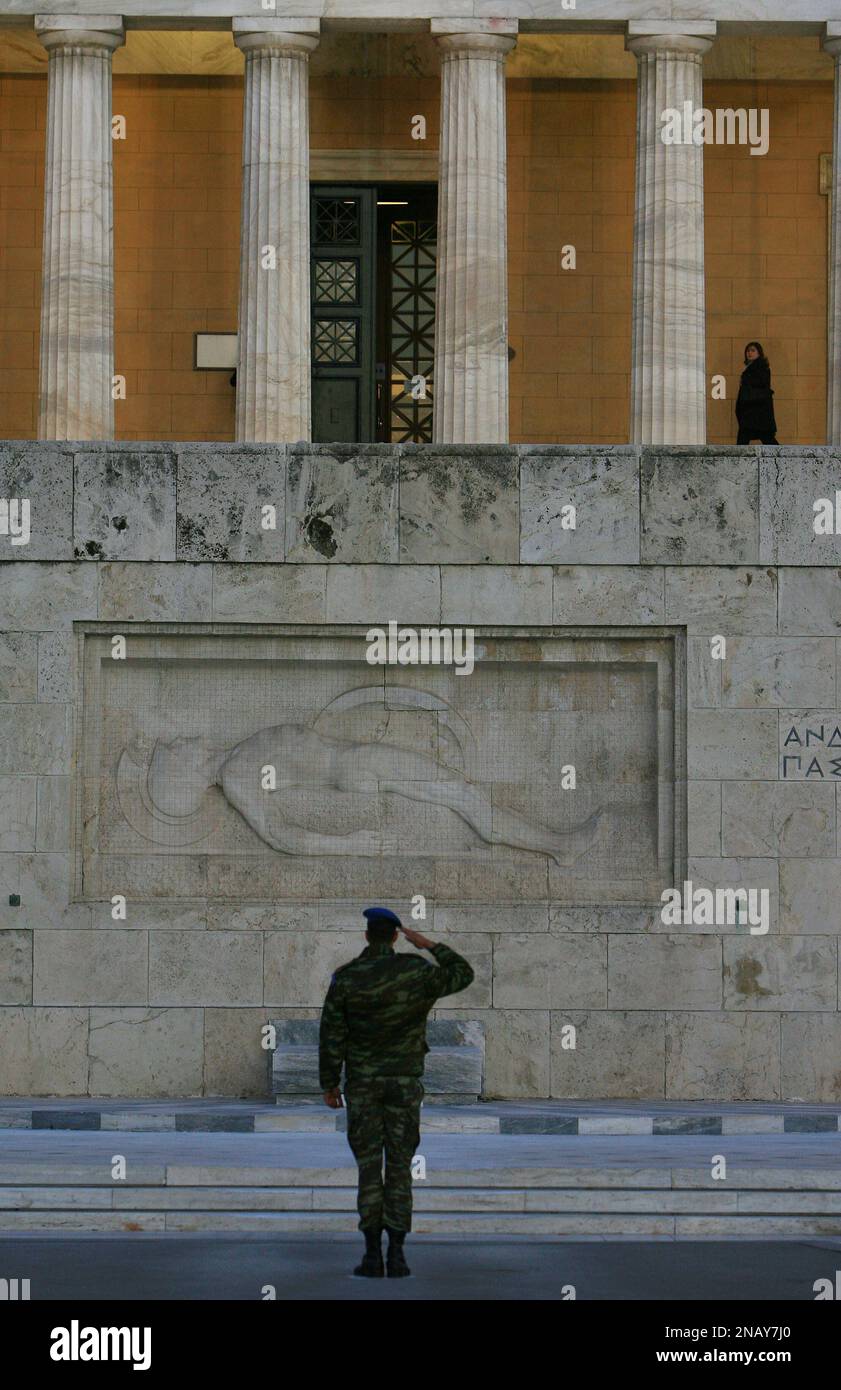 A soldier salutes the tomb of the unknown soldier as a pedestrian ...