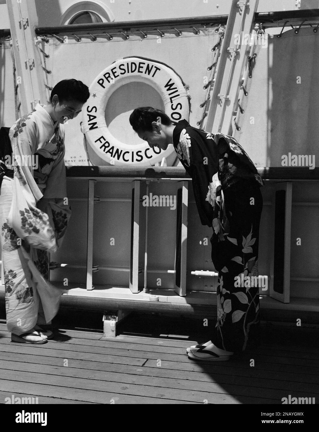 Japanese women give a traditional greeting bow as they meet on board ...