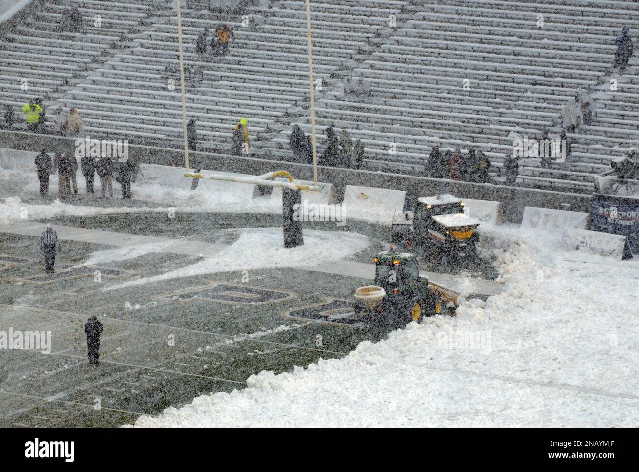 Ground crews try to clear falling snow from the field at Michie Stadium ...