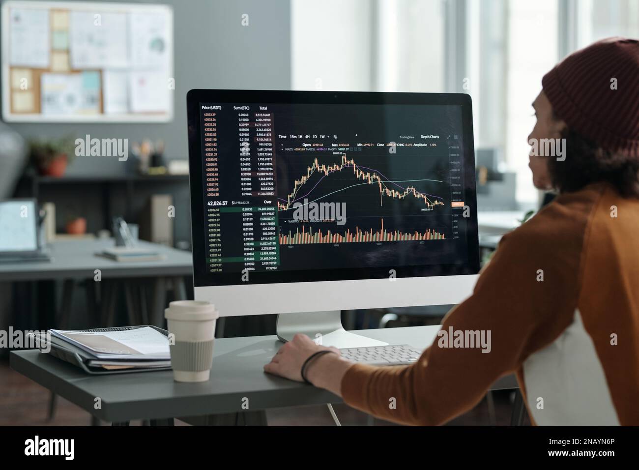 Male analyst sitting in front of computer monitor with graph ...