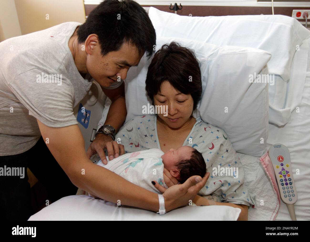 Nongyu Li, at left, holds his yet to be named newborn daughter ...