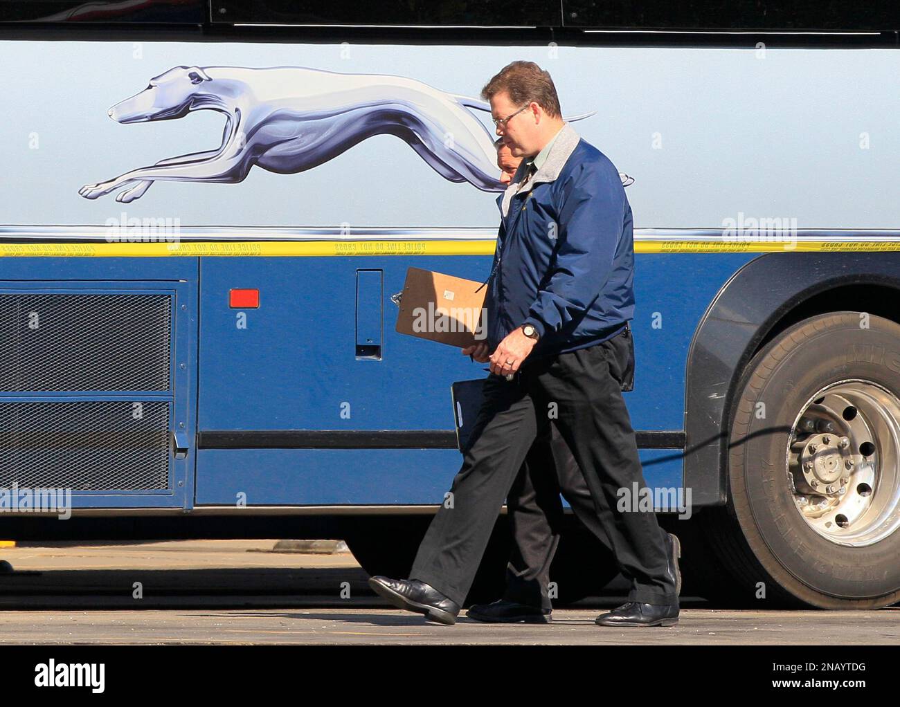 Officials walk past a Greyhound bus surrounded by police tape, Monday ...