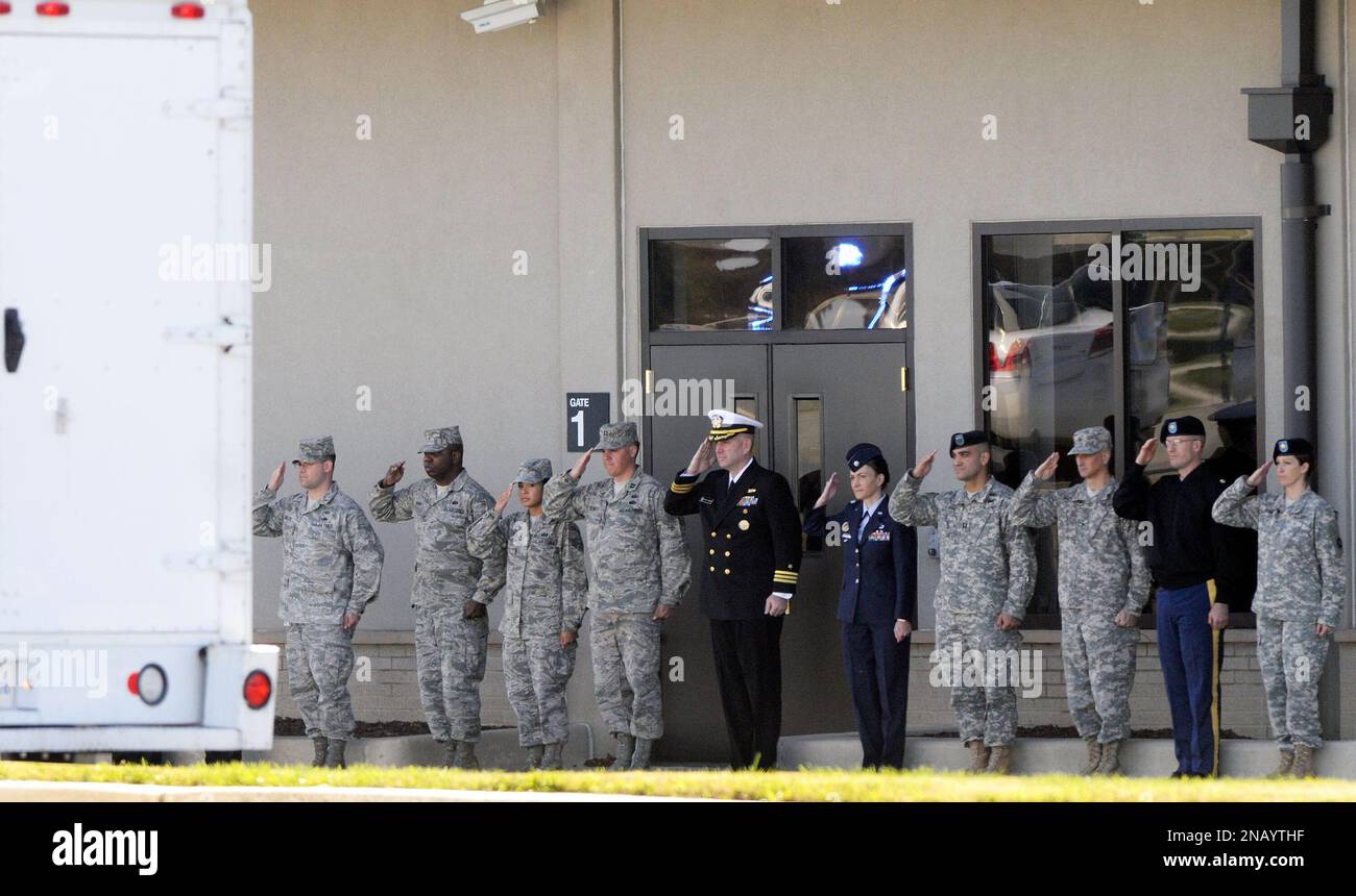 Military personnel salute a transfer vehicle transporting a transfer ...