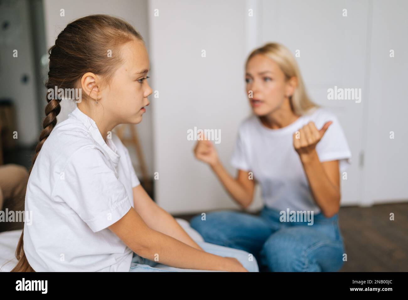 Side view of depressed little girl feeling sad to angry strict blonde ...