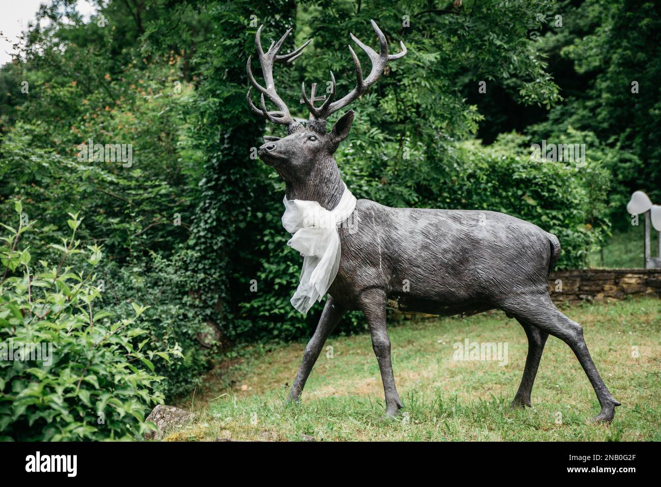 A deer sculpture with white ribbon around its neck in a garden Stock ...