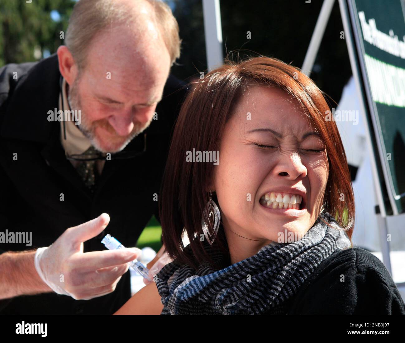 Sue Vang grimaces as she gets a flu shot from pharmacist Patrick O ...