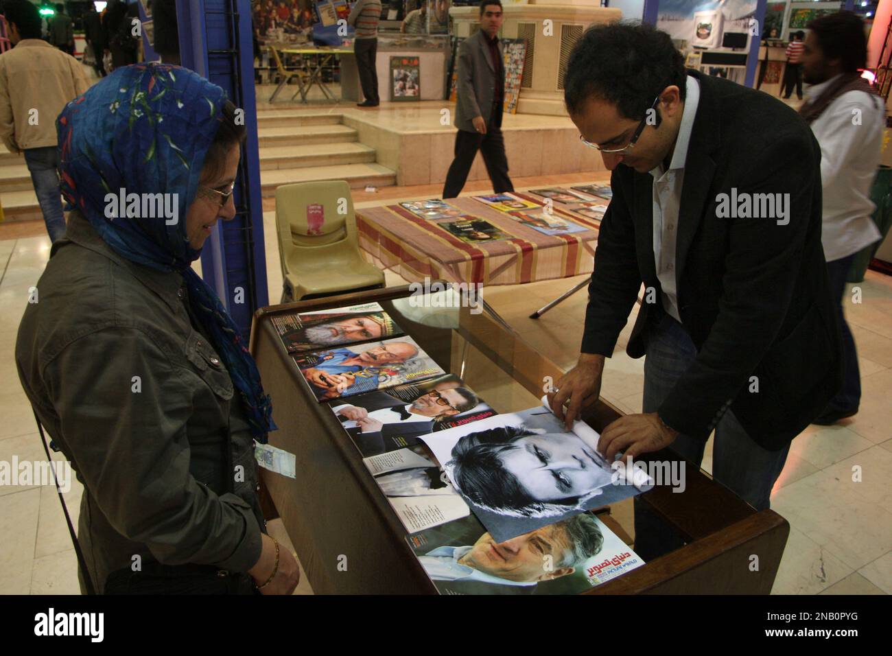 Iranian Hadi Rafiei, right, sells a poster of French actor Alain Delon ...