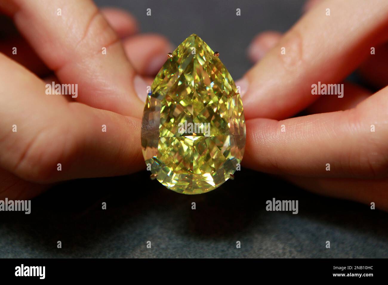 An auction house worker holds a ring with the 'Sun Drop Diamond', 110. ...