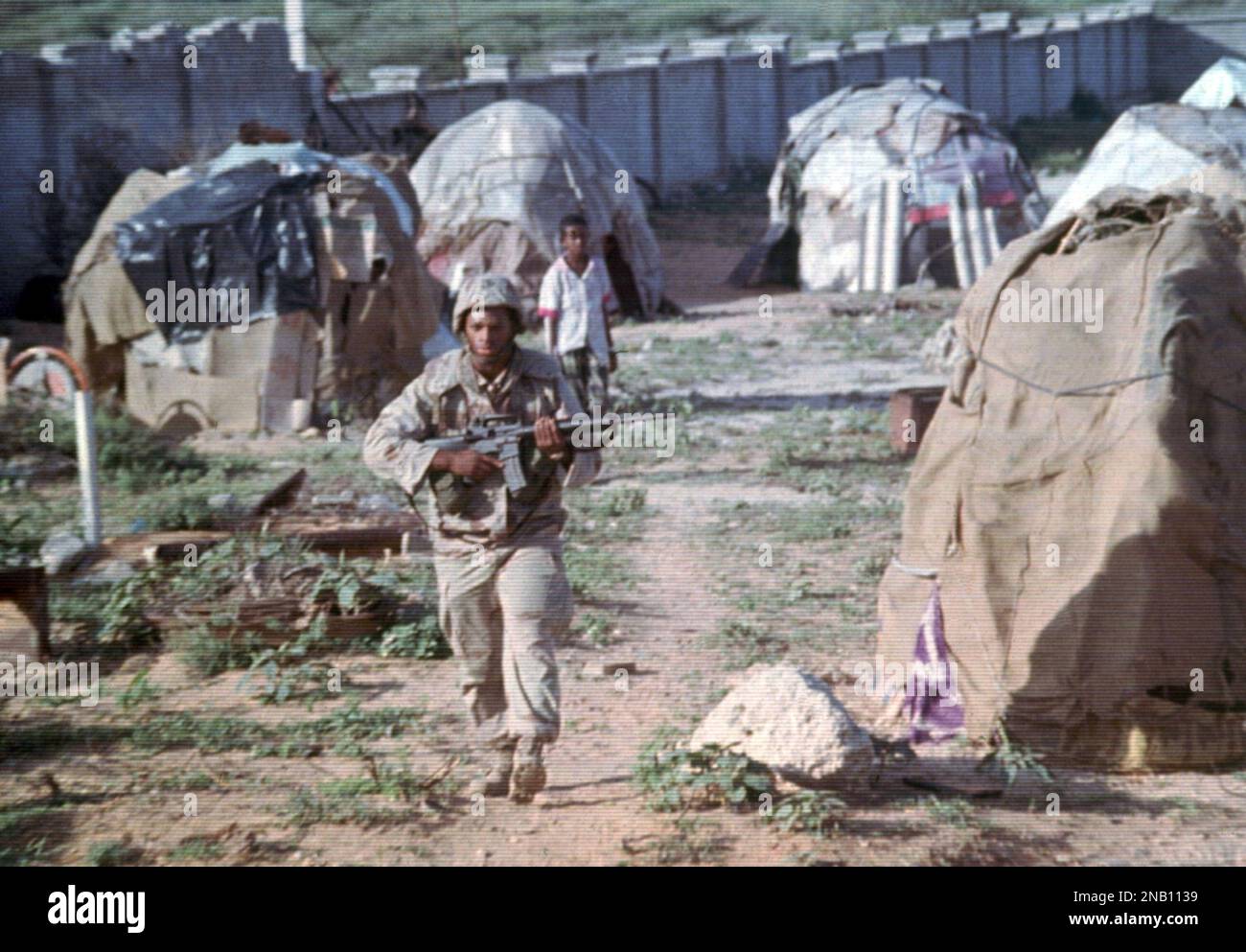 An armed United States Marine patrols through a temporary camp in ...
